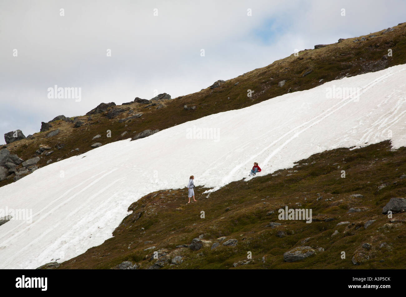 Two girls sliding down snow along Hatcher Pass Road , Alaska Stock ...