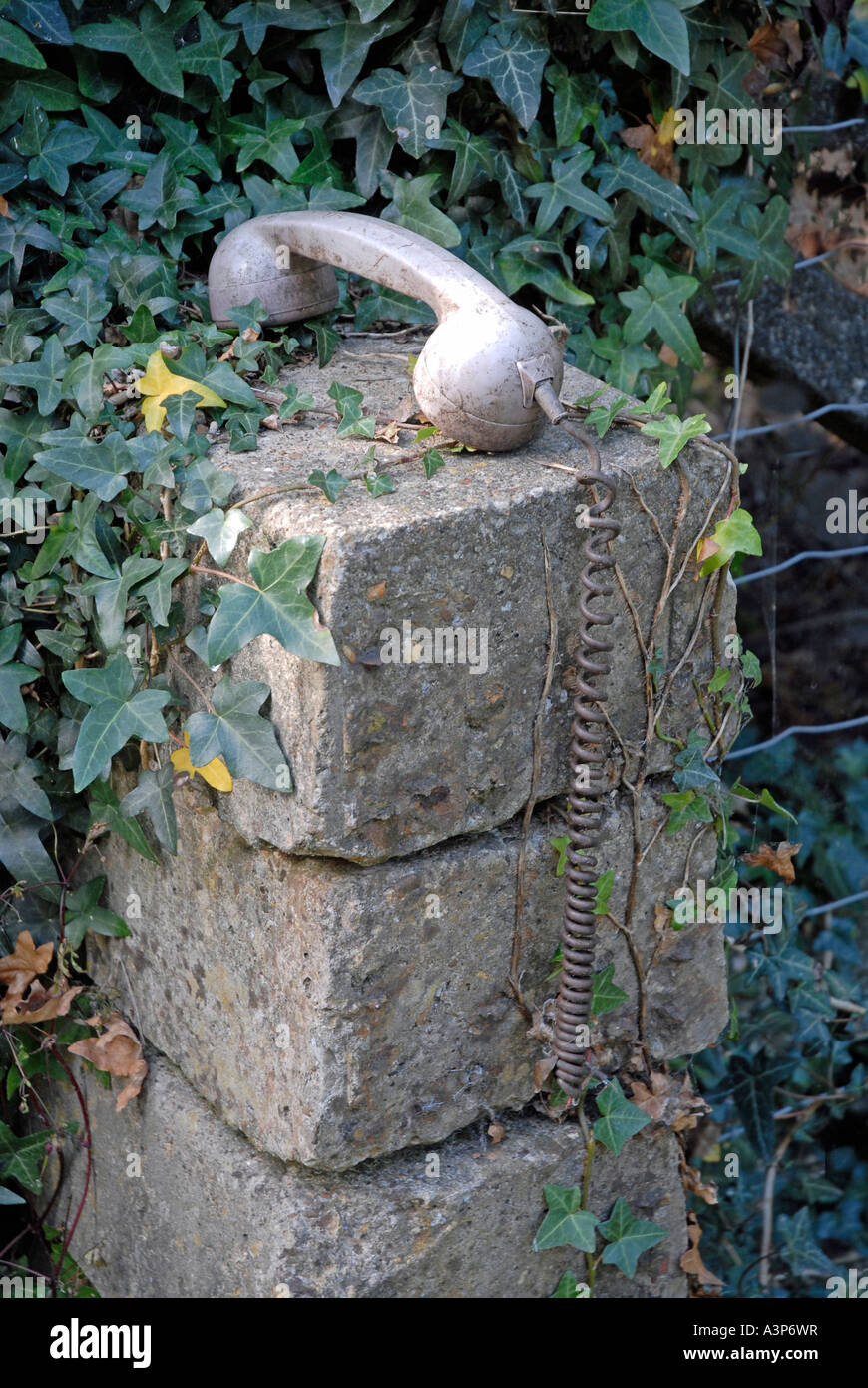 Abandoned telephone handset on pillar of stone blocks beside railway ...