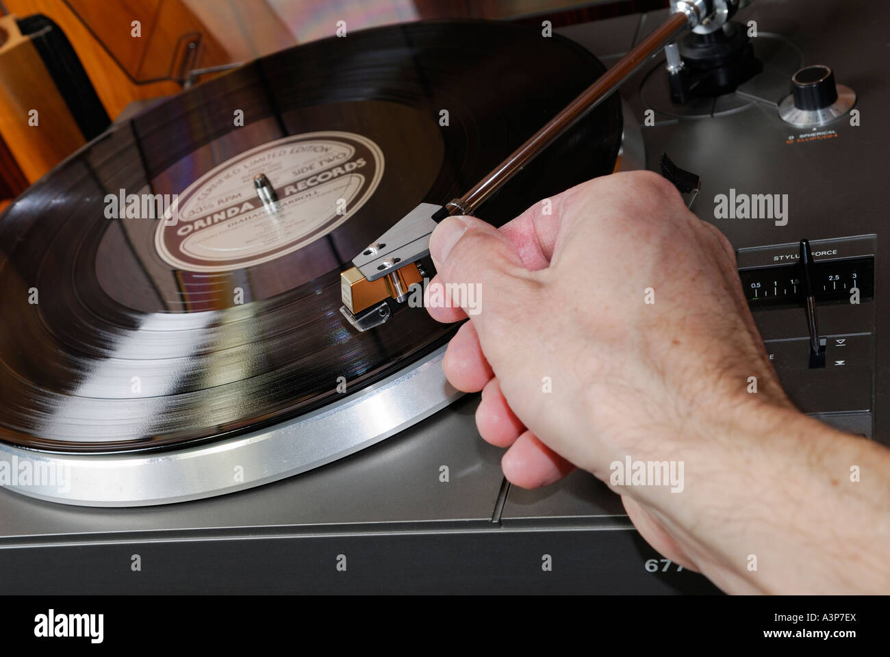 Man dropping the stylus needle arm of a turntable on a long playing ...