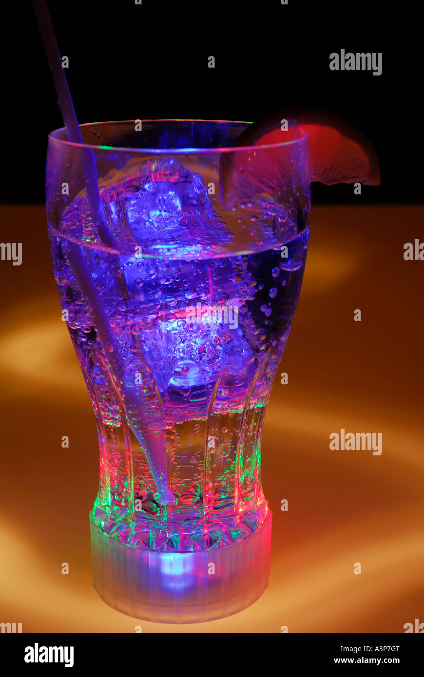 Sparkling clear alcoholic beverage at a night club with colored lights ...