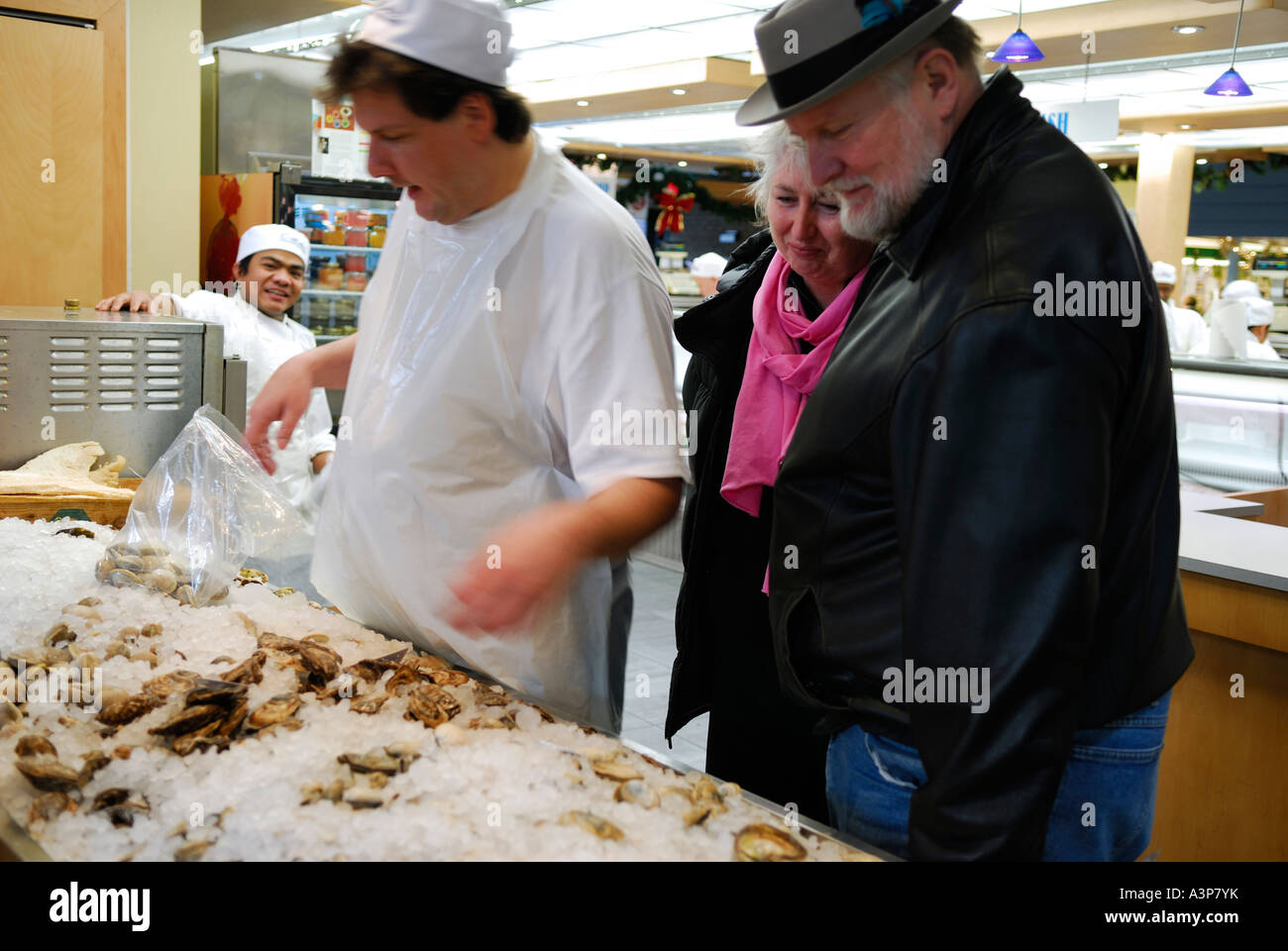 Market shoppers entertained by fish monger assistance picking clams ...
