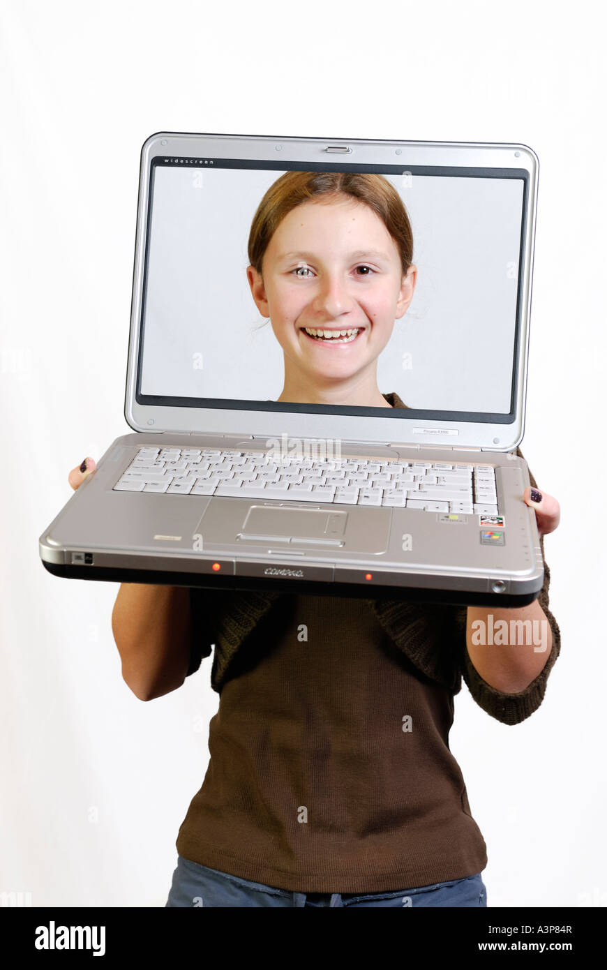 Laughing teenager girl holding up a laptop with her face on the screen ...