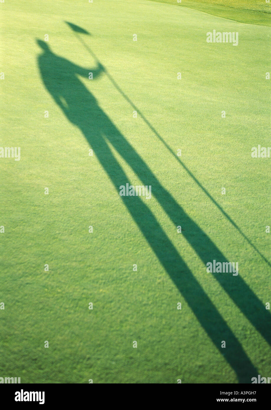 Shadow of golfer holding golf flag Stock Photo - Alamy