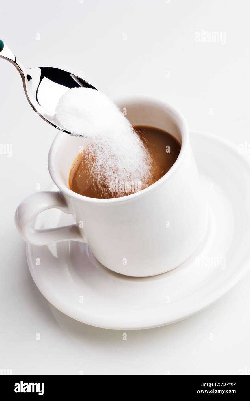 Spoon pouring sugar into a cup of coffee Stock Photo - Alamy