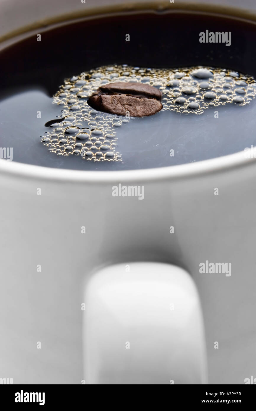 Cup of coffee with a bean floating in the coffee Stock Photo - Alamy