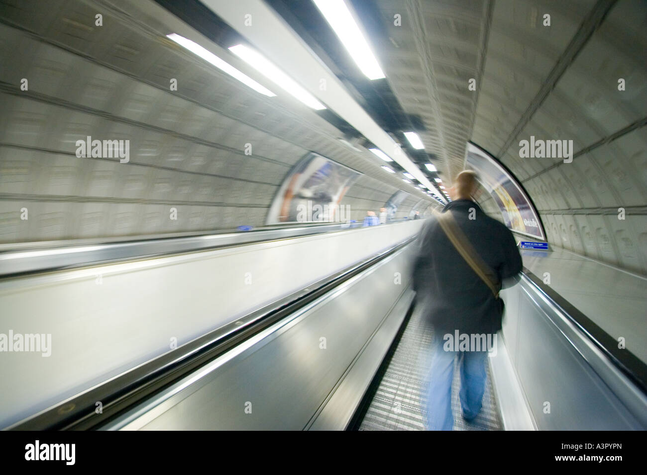 man walking down connecting corridor on moving pavement on london ...