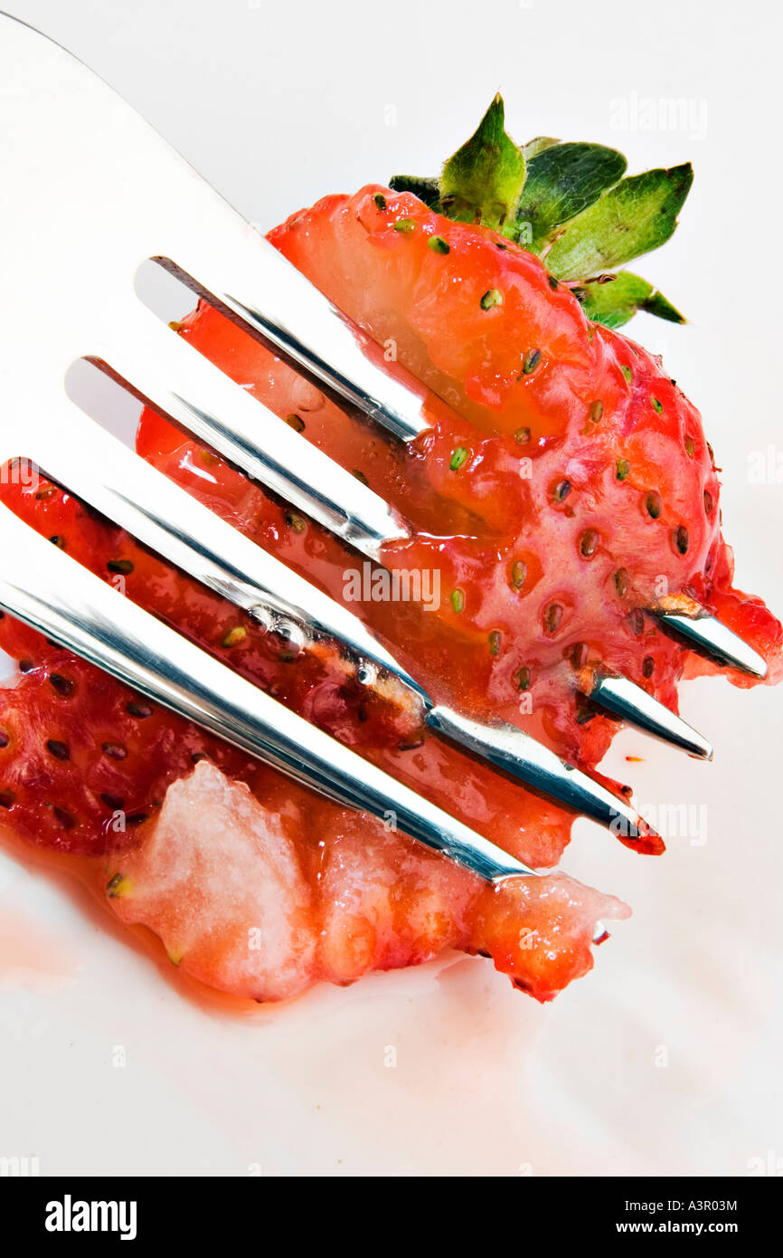 Strawberry being smashed by a fork Stock Photo - Alamy