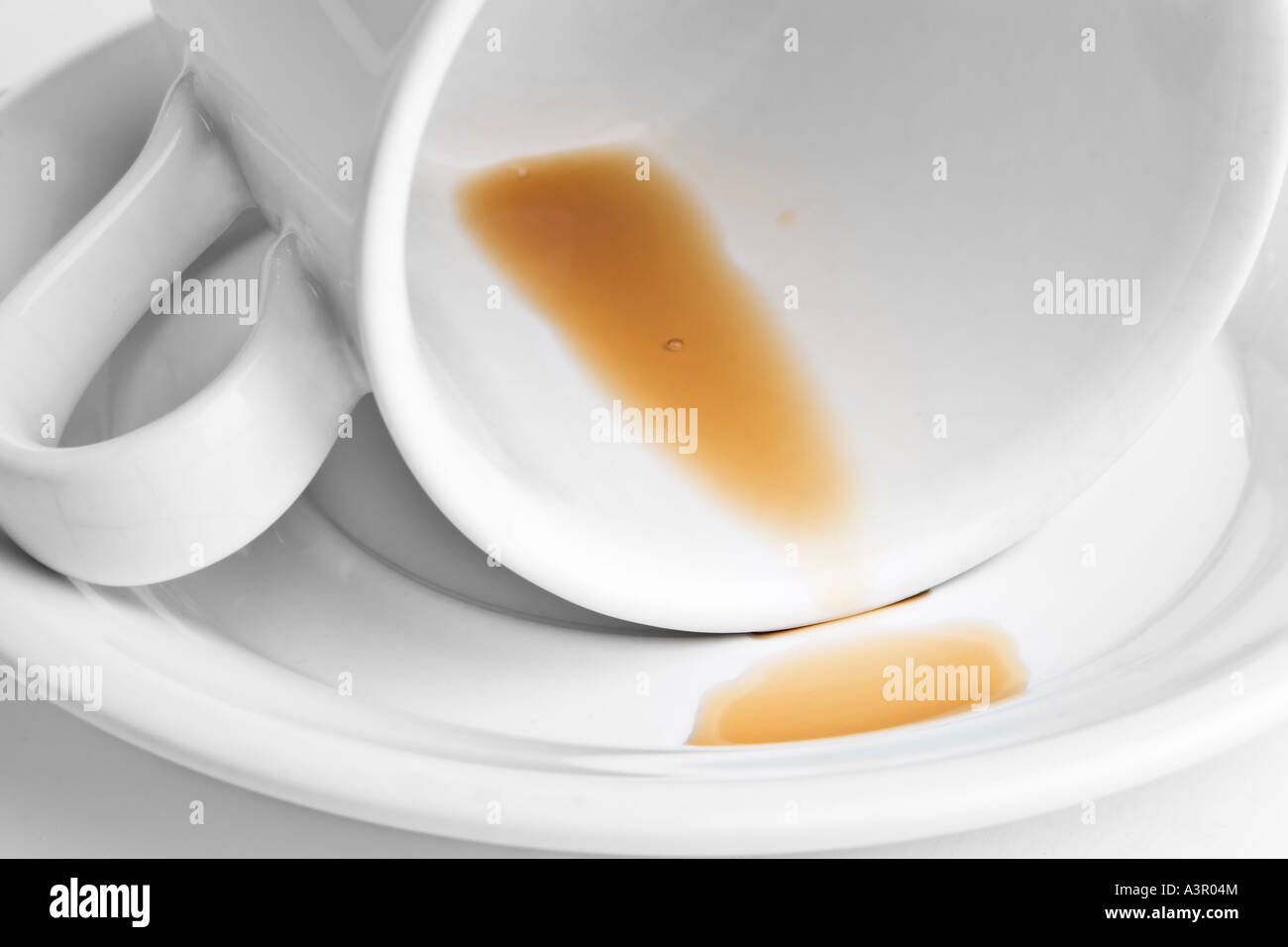 Cup of coffee turned on its side with only a few drops of coffee left ...