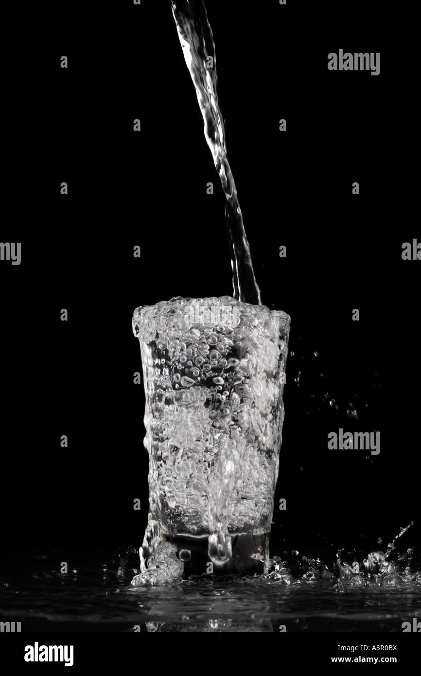 Pouring water overflowing the glass Stock Photo - Alamy