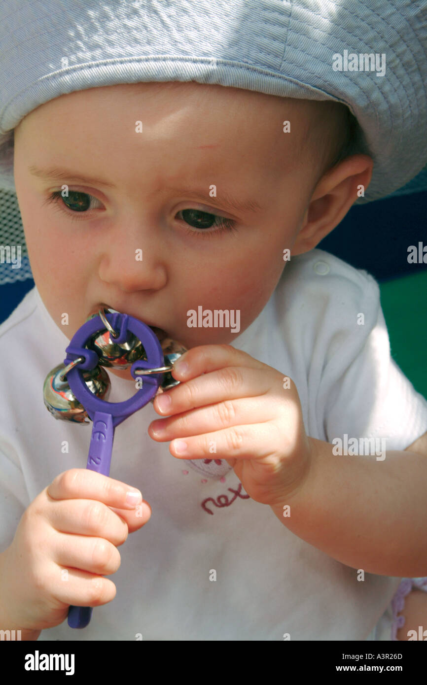 baby girl biting a toy rattle Stock Photo - Alamy
