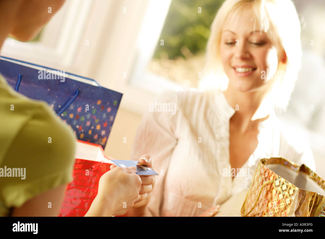 Young blonde woman paying for goods in shop Stock Photo - Alamy