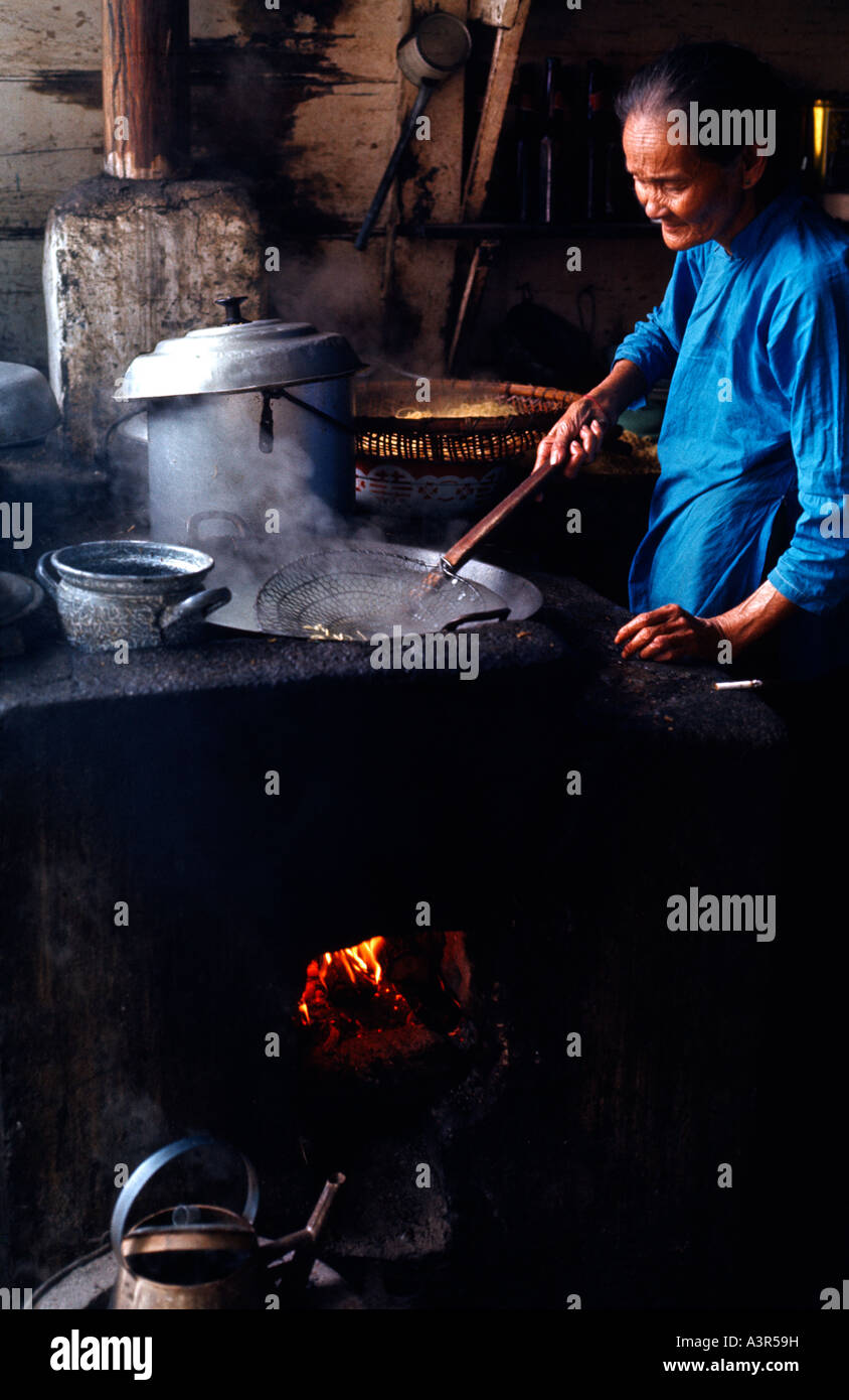 Old Chinese woman cooking noodles in a restaurant in Balige Lake Toba ...