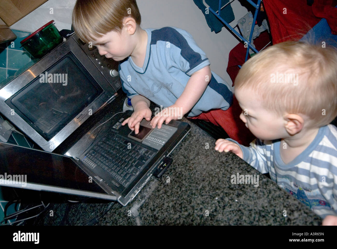 One child using a laptop ,one child watching Stock Photo - Alamy