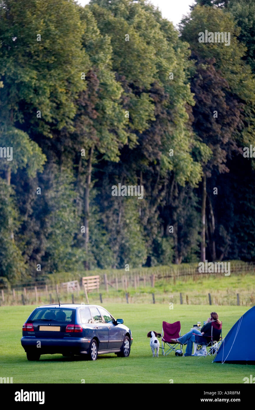 Person relaxing on a campsite reading a book in the early evening, in a ...