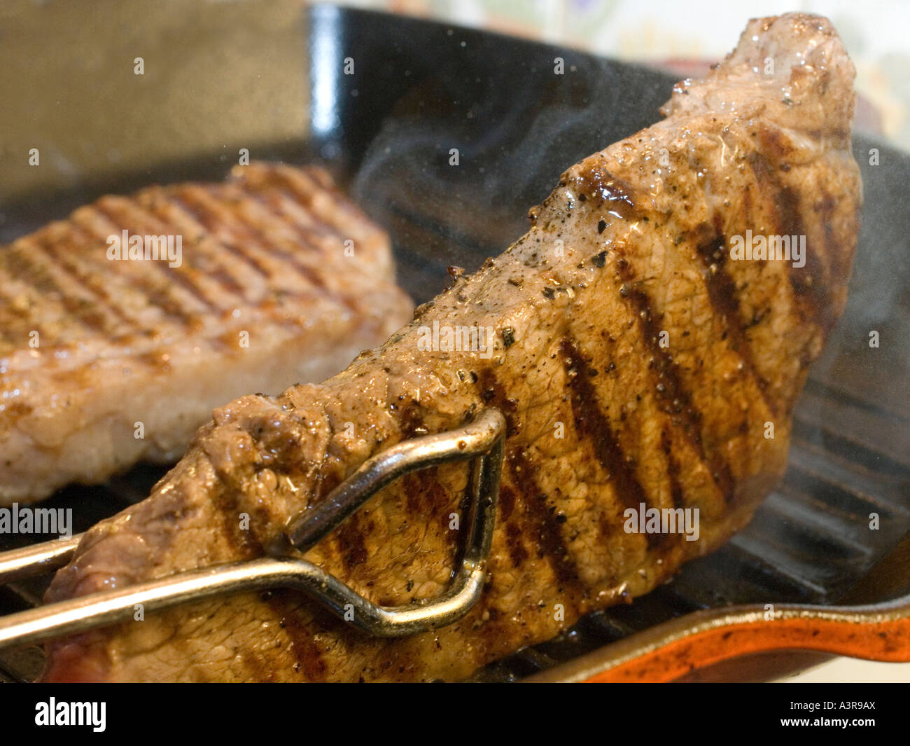 Steaks being cooked in frying griddle pan Stock Photo - Alamy