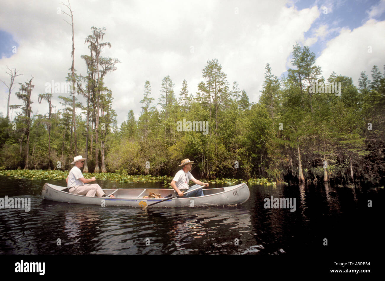 Okefenokee swamp in Southern USA with canoe on lake waters with two men ...
