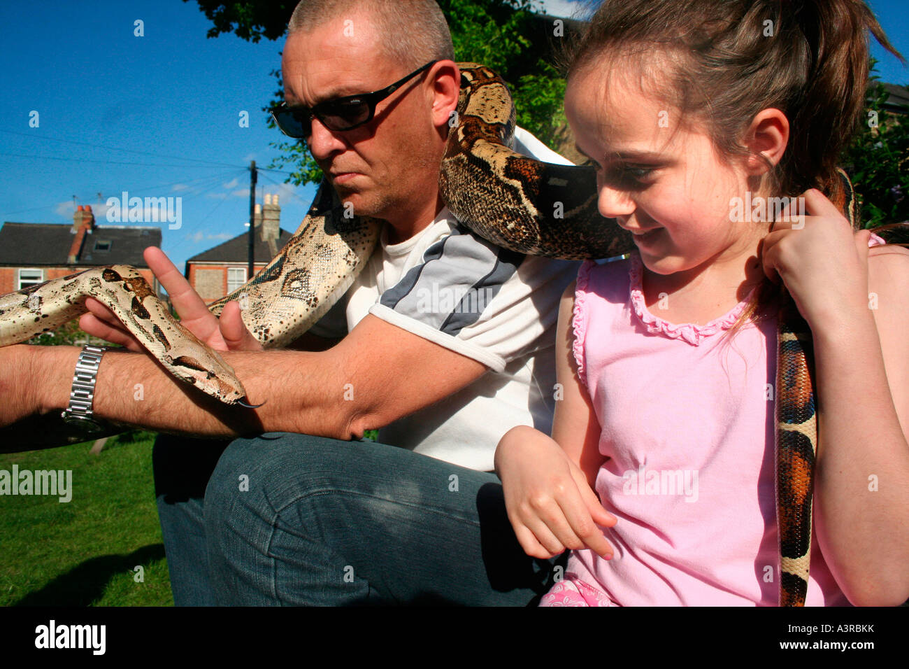 Man shows child pet snake she looks nervous Stock Photo - Alamy