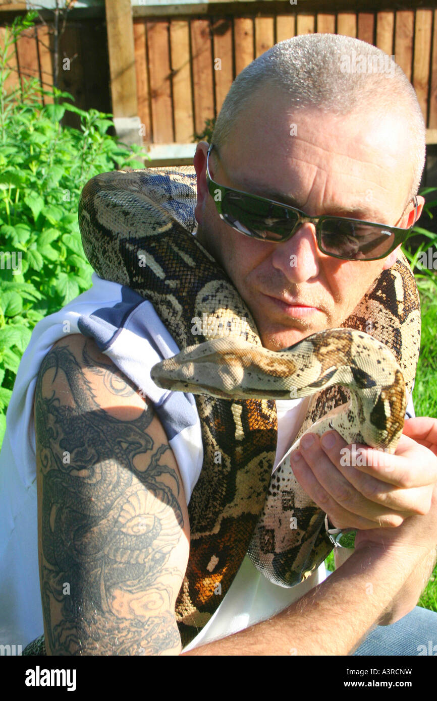 tough guy with tattoos handling a pet snake Stock Photo - Alamy