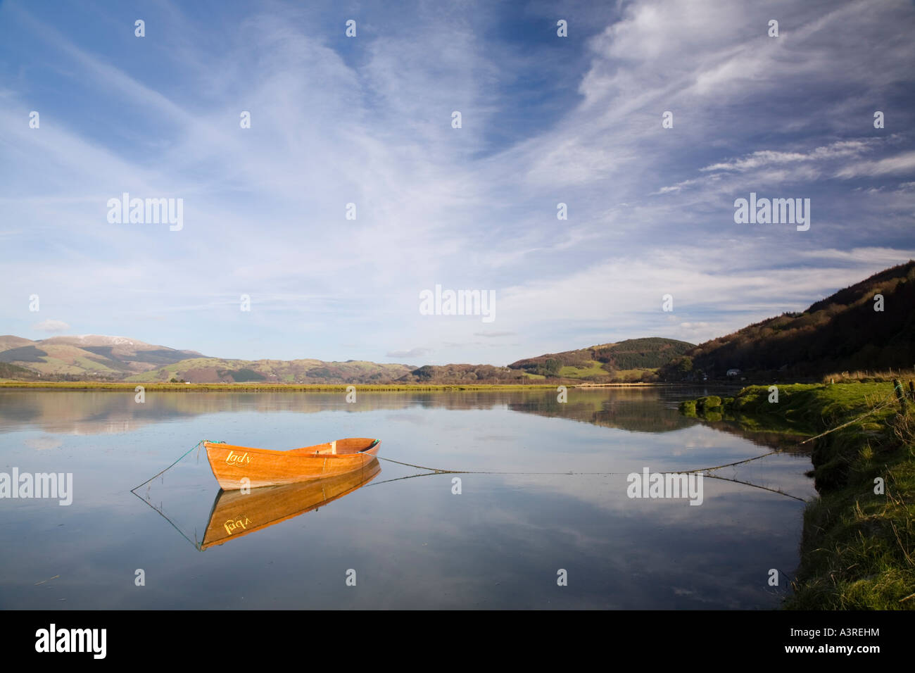 Scenic rural view with wooden rowing boat reflected in calm water on ...