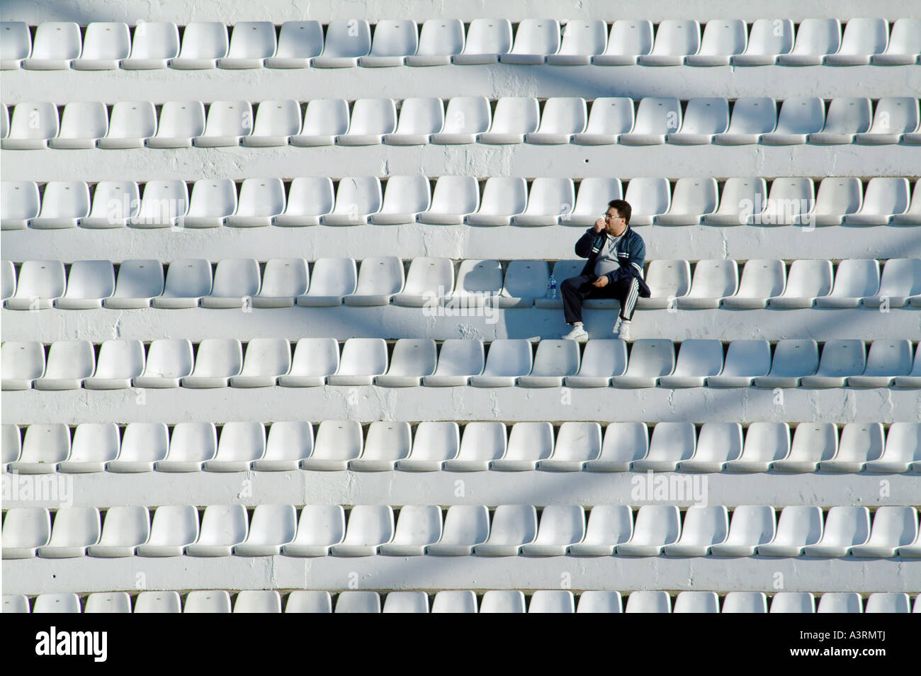 Lonely man sitting on stands of a football stadium Stock Photo - Alamy
