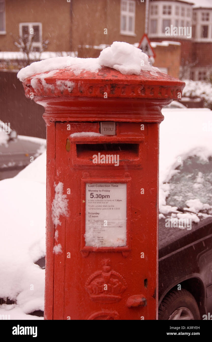 snow covered red mail box, London, England with houses and parked car ...