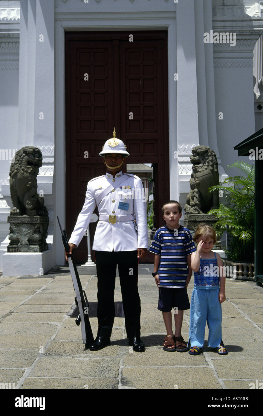 Two European children stand beside an immobile armed guard in uniform ...