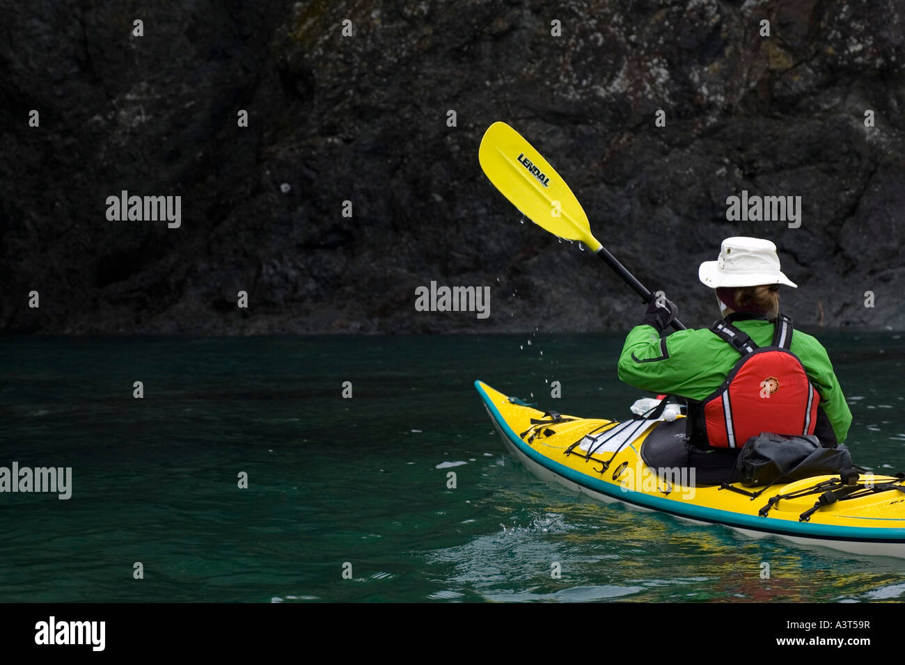 A female sea kayaker explores a sea cave in Lake Superior Provincial ...
