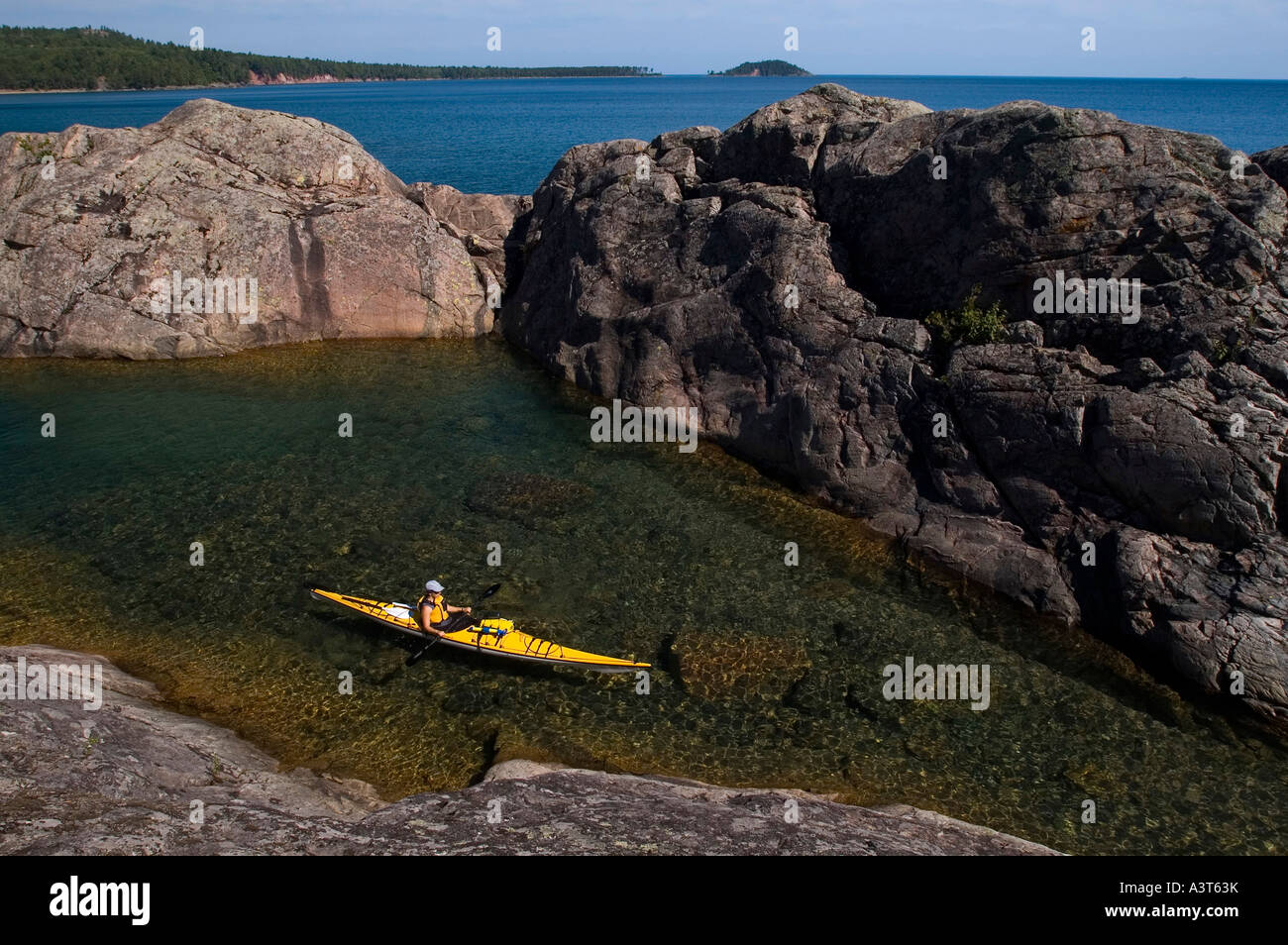A sea kayaker explores a protected cove with rock walls on Lake ...