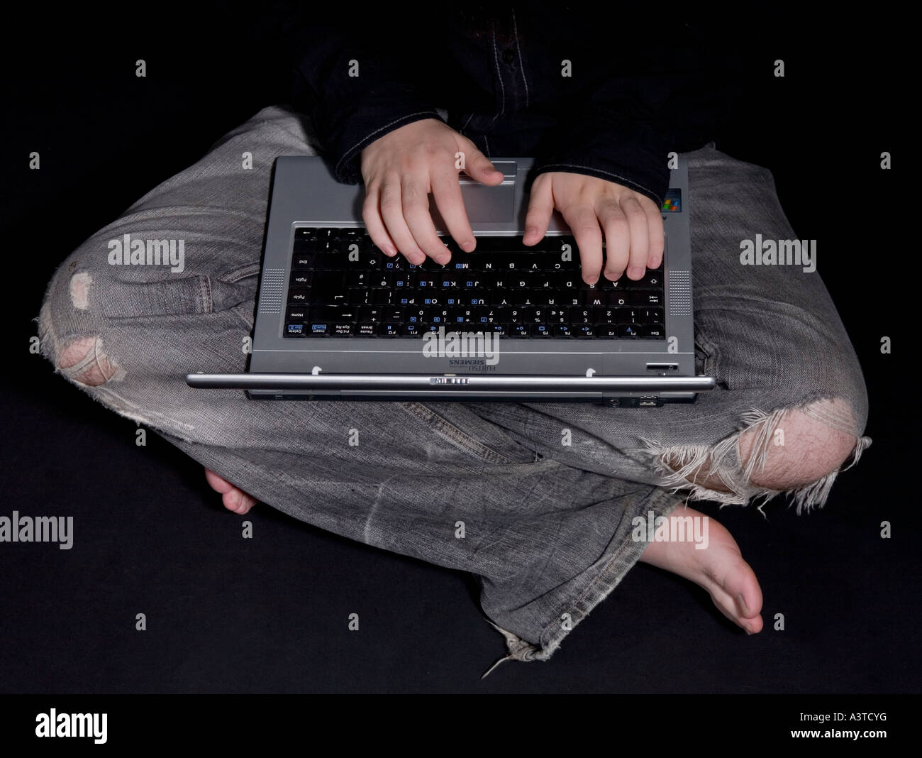 Young man in ripped jeans and bare feet on a laptop computer Stock ...