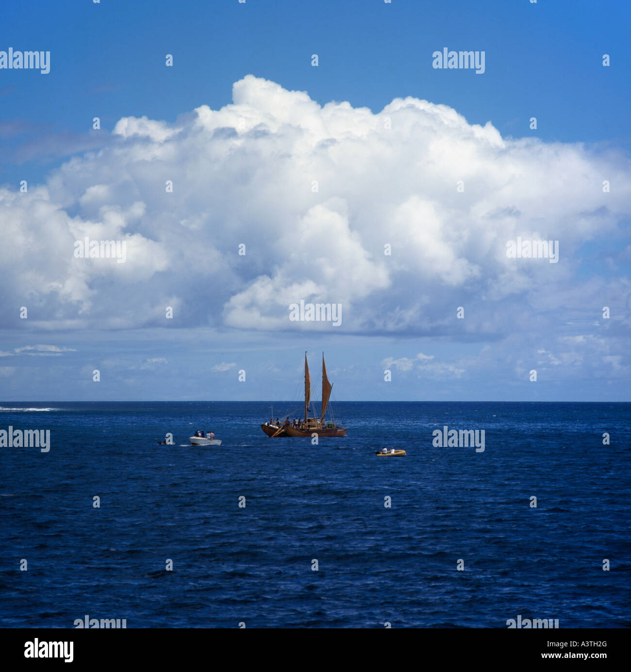 Traditional Pacific sailing canoe with twin masts and red sails leaves ...