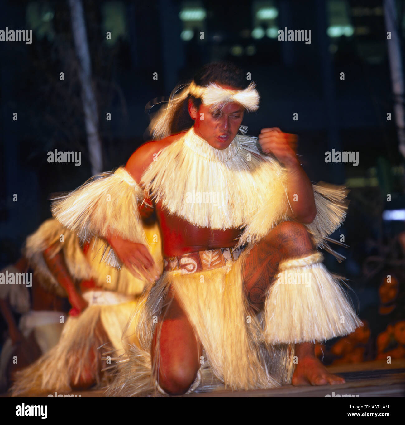 Tahitian dancer at night in traditional dress wears grass skirt top ...