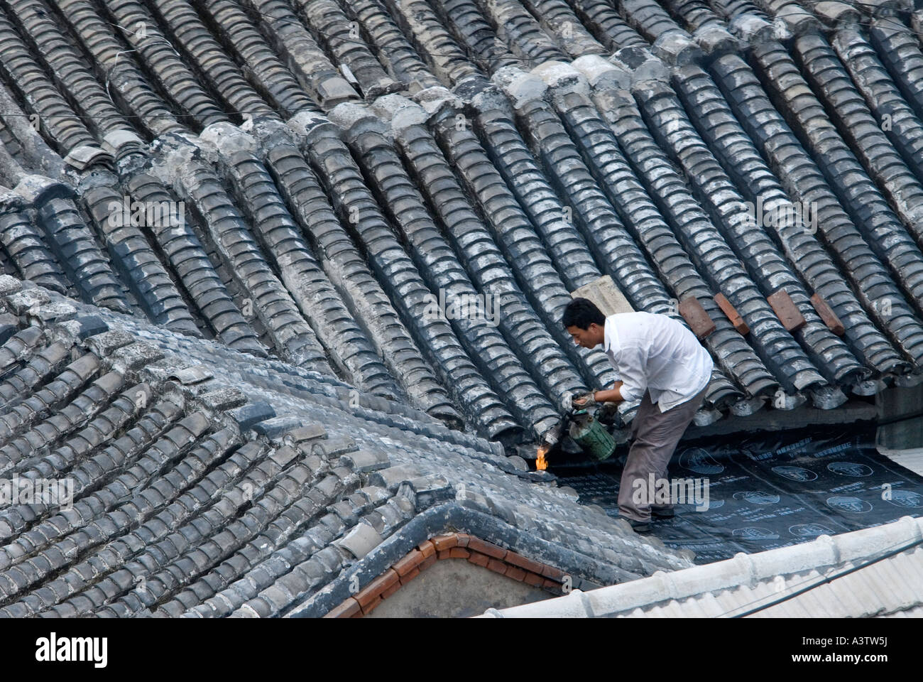 Chinese man repairing his roof in Beijing Hutong China Stock Photo - Alamy