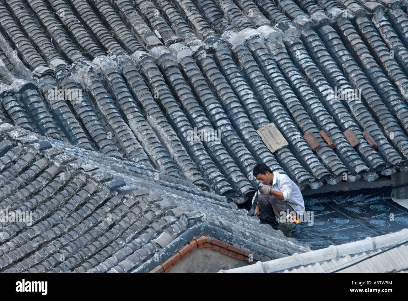 Chinese man repairing his roof in Beijing Hutong China Stock Photo - Alamy