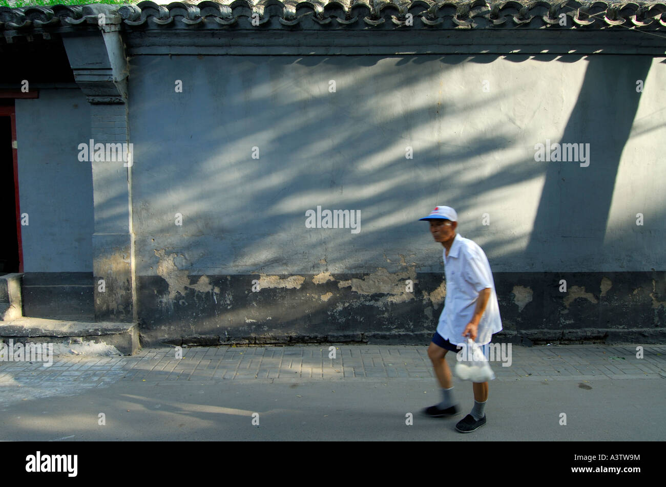 Elderly Chinese man with plastic bag walking in the lanes of Beijing ...