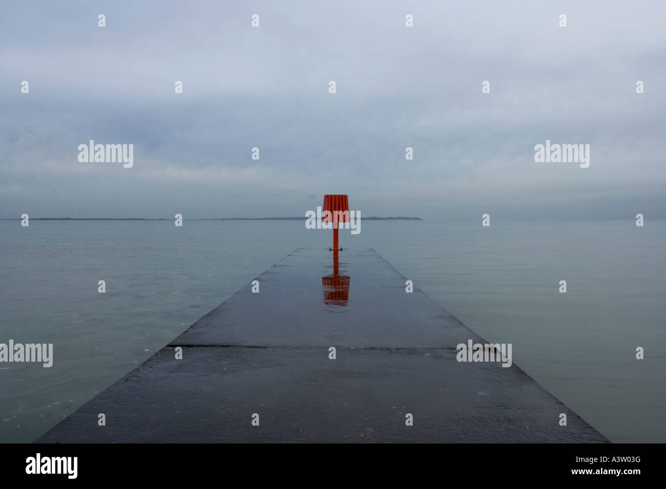 Red jetty marker reflection on overcast day Stock Photo - Alamy