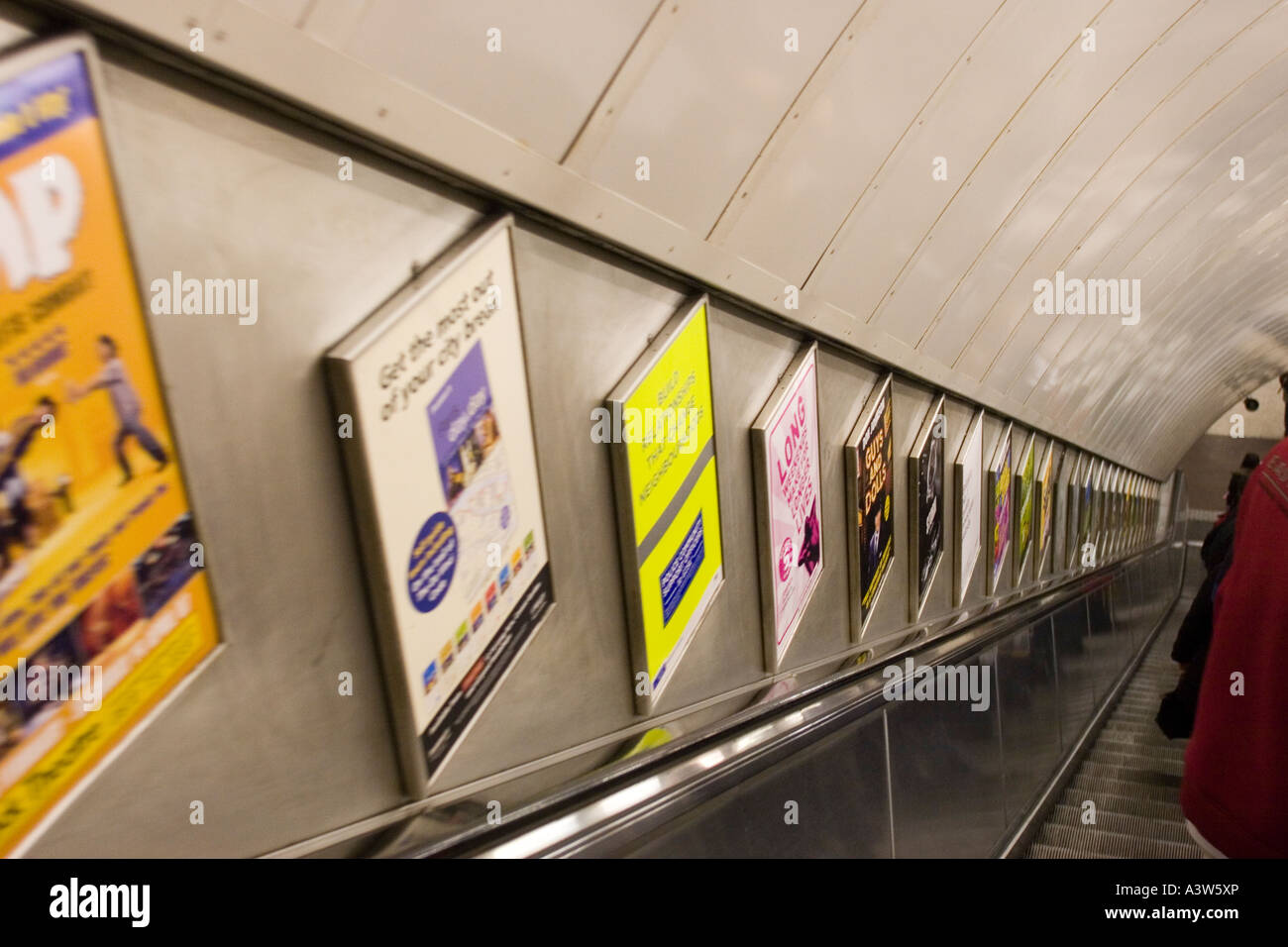 View down an escalator in the London underground with advertising ...