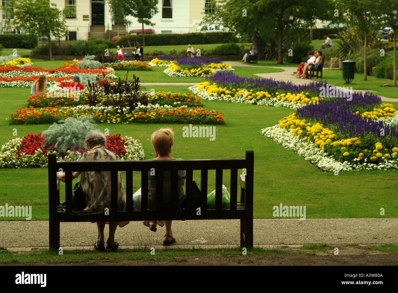 Ladies chat sitting on park bench in floral gardens Imperial Gardens ...