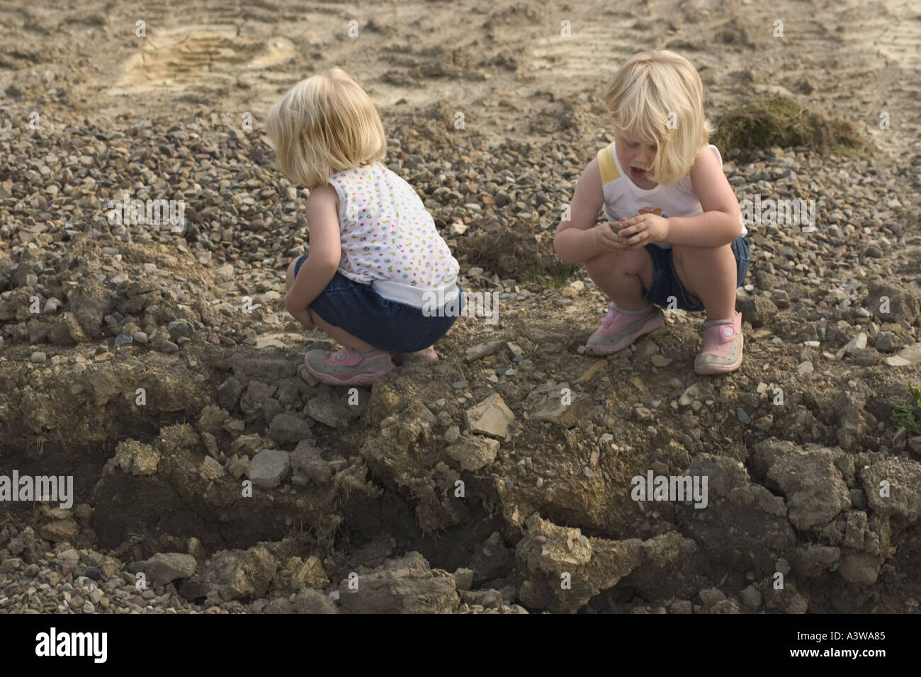 twin girls picking up rocks Stock Photo - Alamy