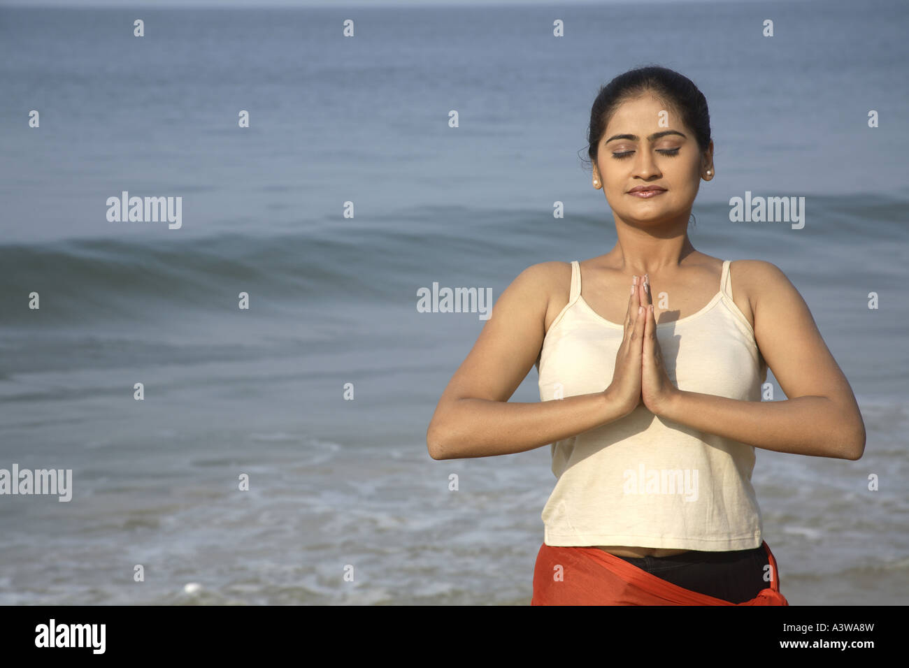 Indian woman exercising hands folded namaste yoga asana on the beach ...