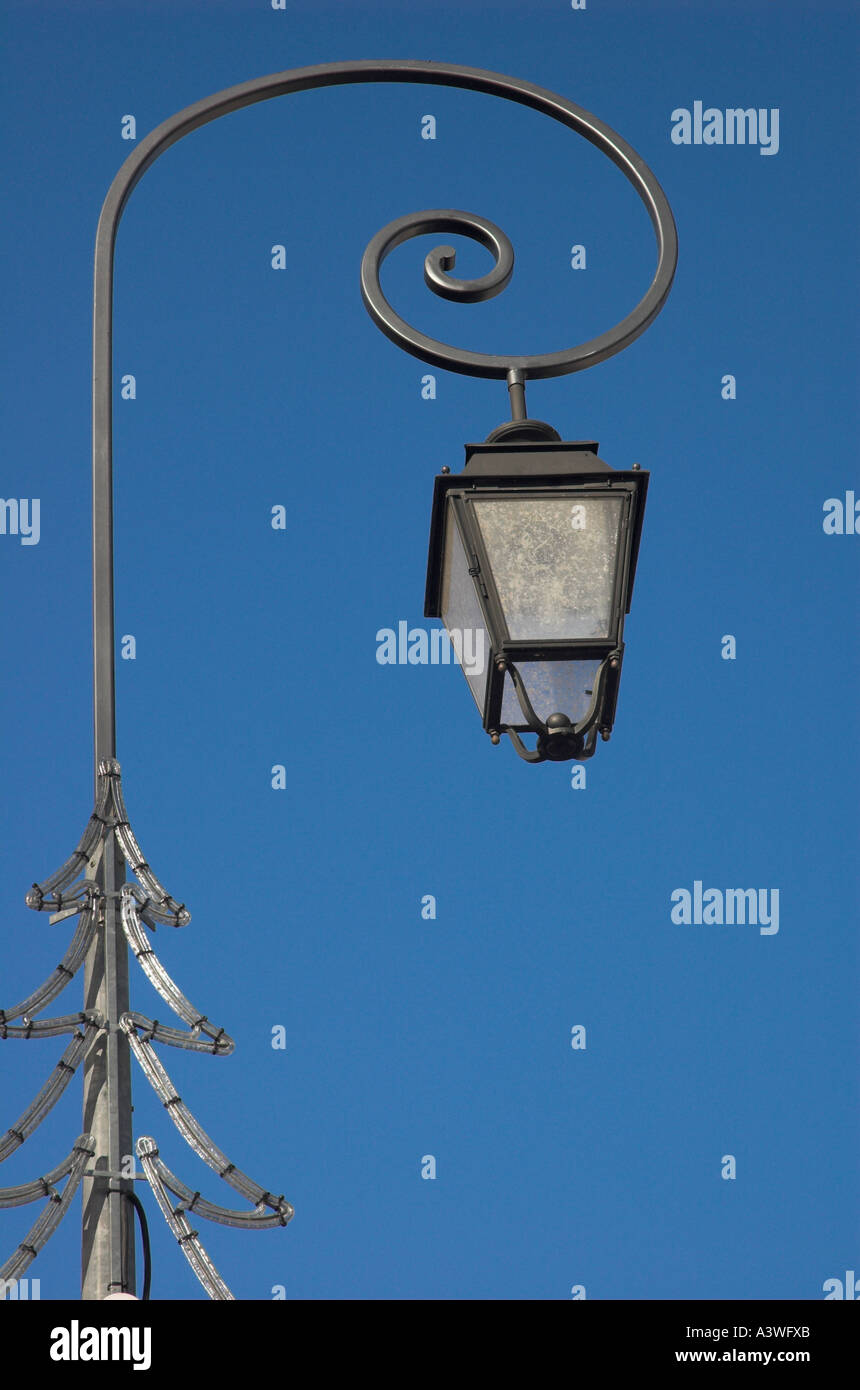 A traditional street lantern hanging from a curved iron crook with a ...