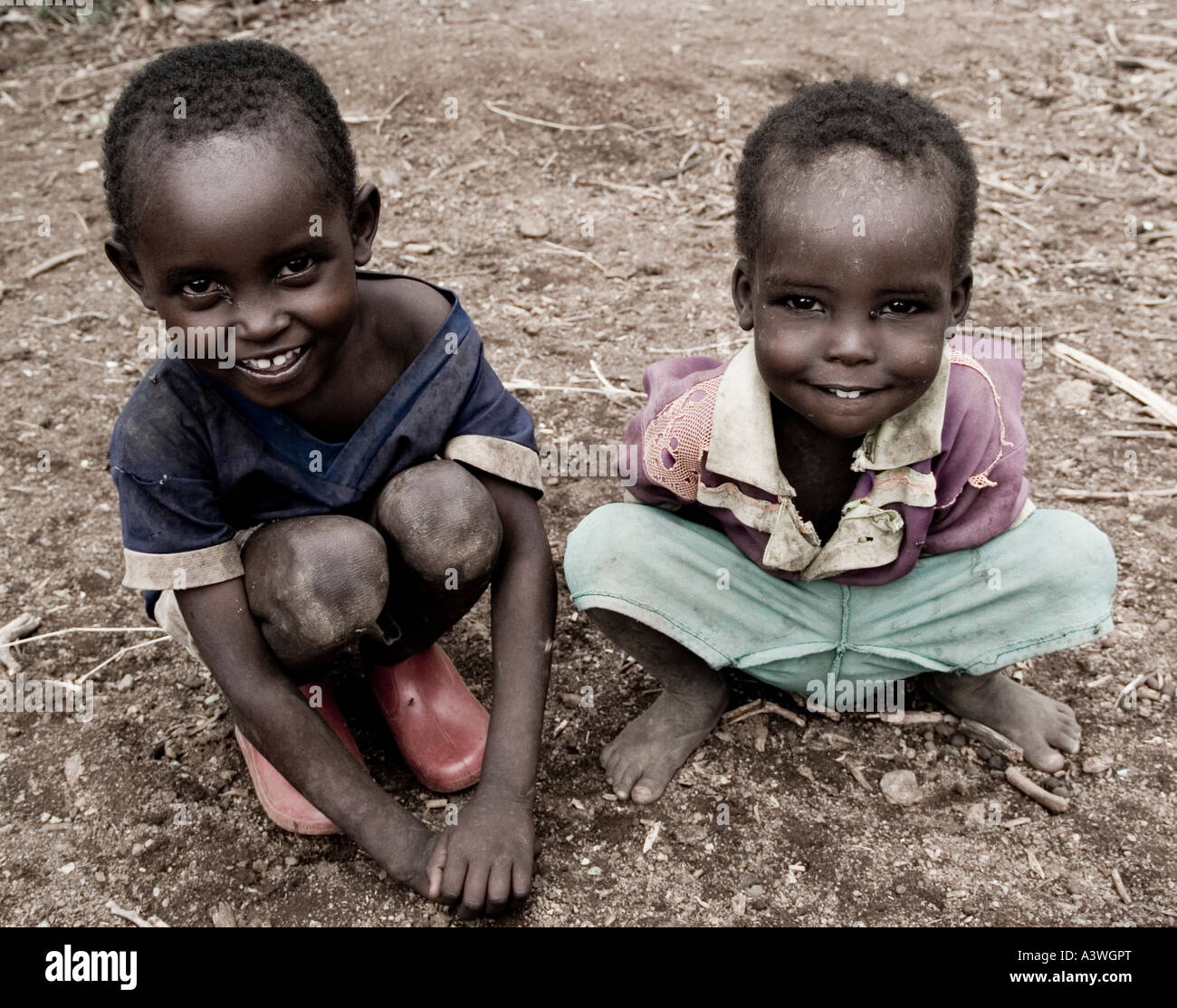 two young boys squat in the dirt in a kenyan village Stock Photo - Alamy