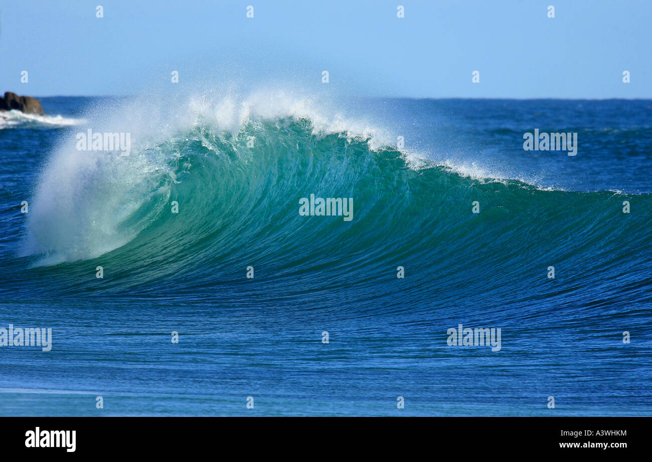 A blue wave breaks on a blue sky day Stock Photo - Alamy