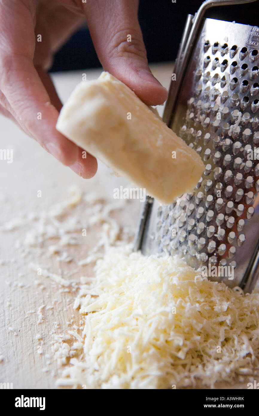 hand grating parmesian cheese with grater close up Stock Photo - Alamy