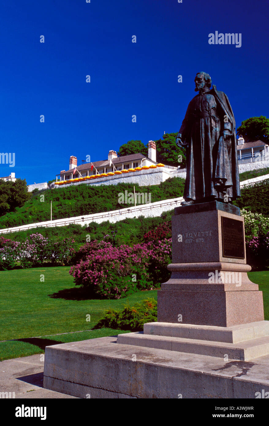 A STATUE OF FATHER JACQUES MARQUETTE STANDS AMON BLOOMING LILACS ON THE ...