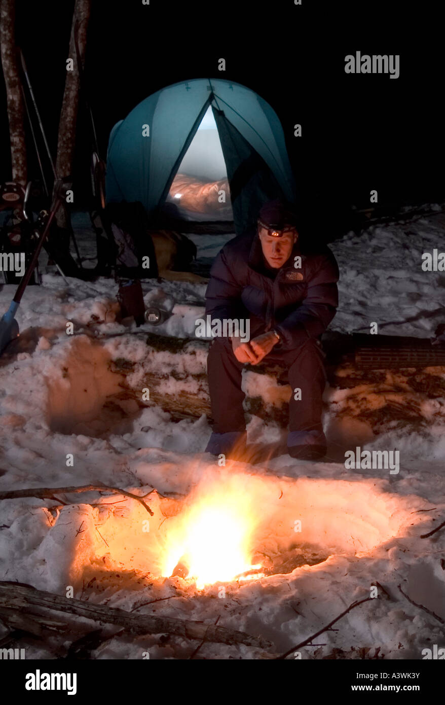 A winter camper and his dog relax around a campfire in the Porcupine ...