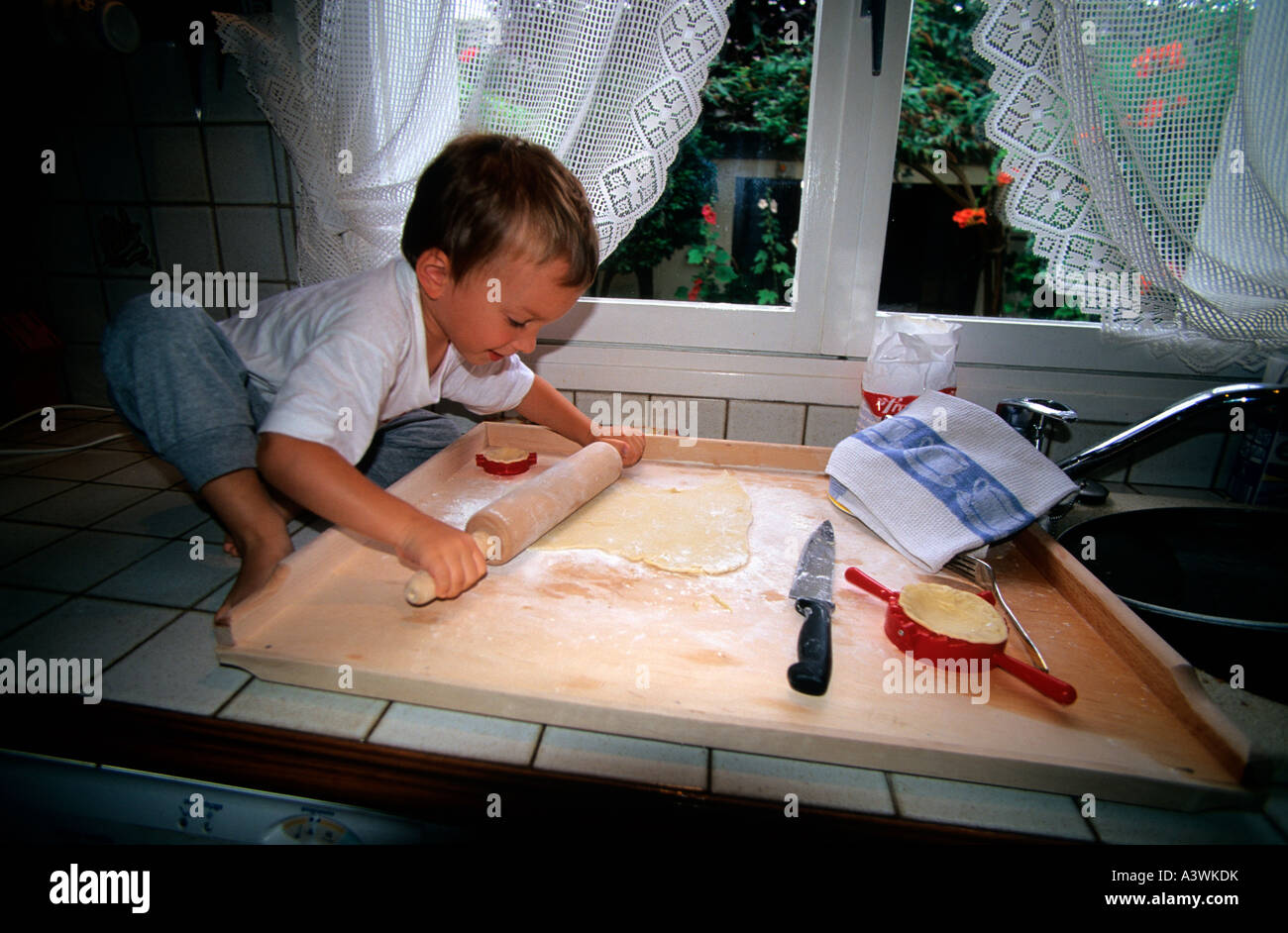 Child pin pinning out pastry on kitchen table Stock Photo - Alamy
