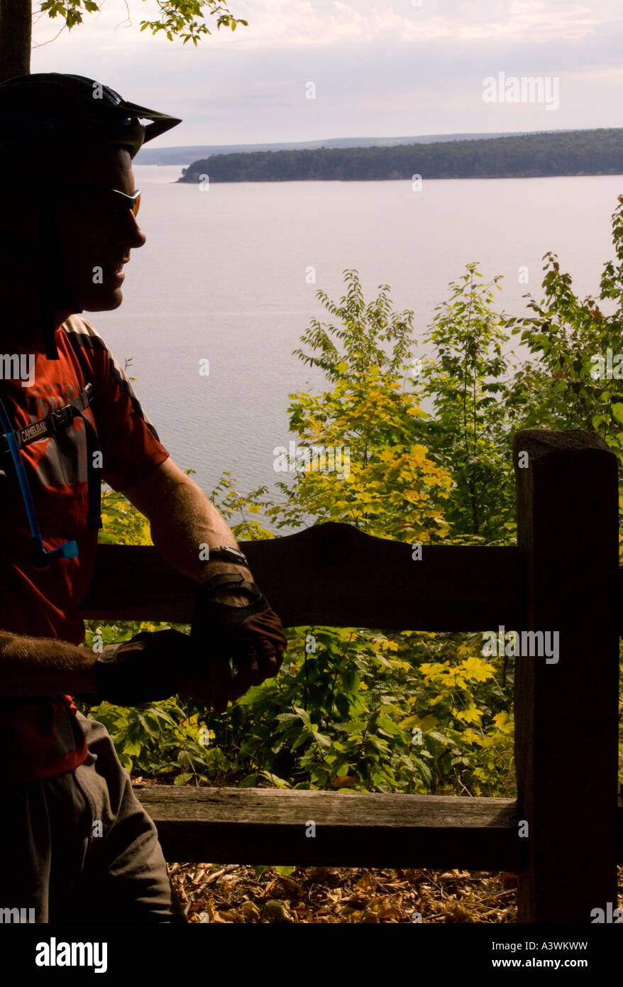 A mountain biker stops at an overlook of Trout Bay on Grand Island ...