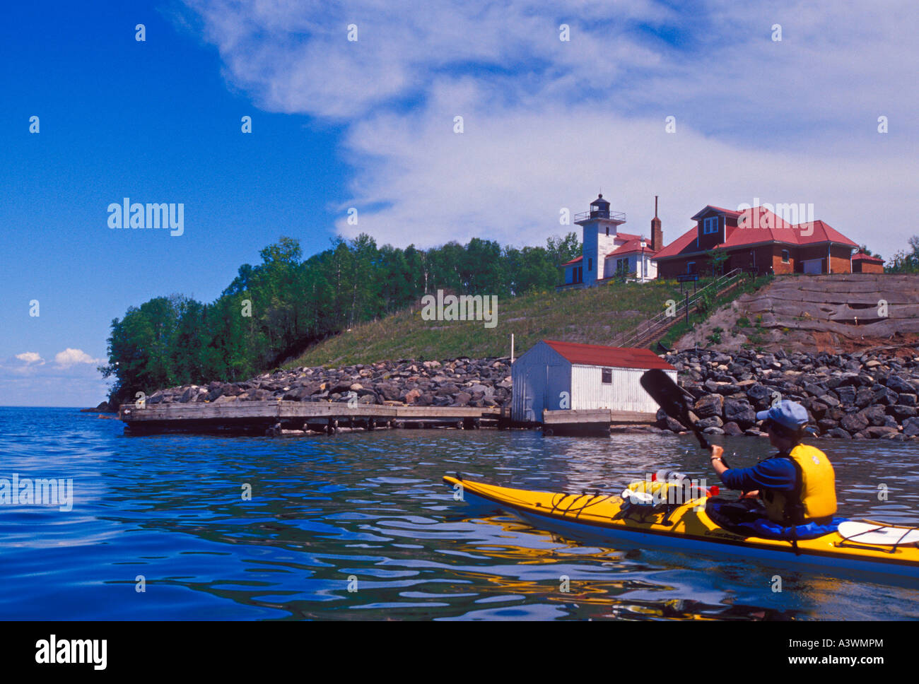 A sea kayaker paddles past the Raspberry Island Lighthouse in Apostle ...
