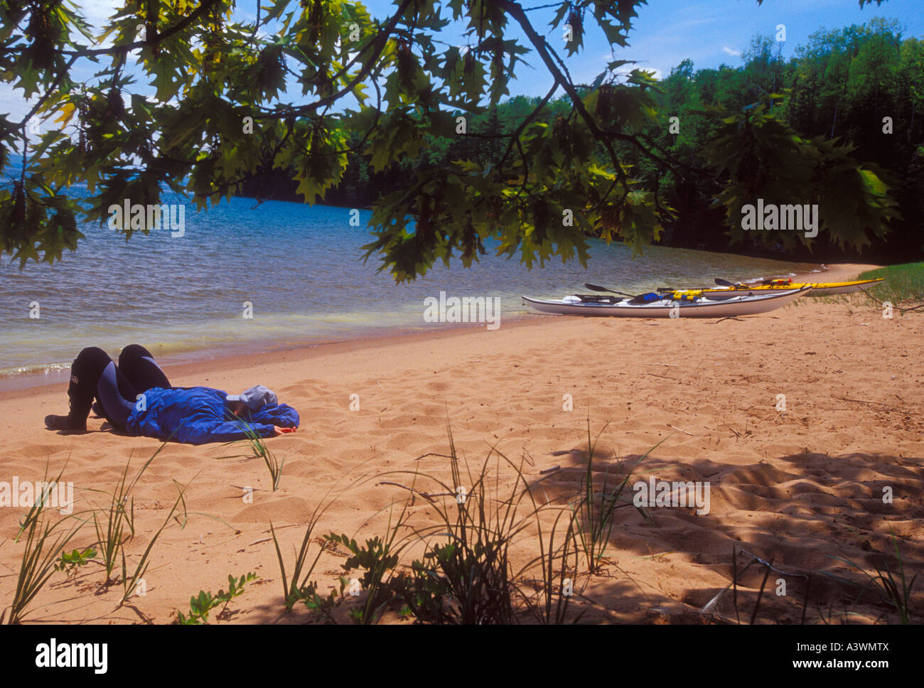 Sea kayaks beached on Stockton Island as a paddler rests in the Apostle ...