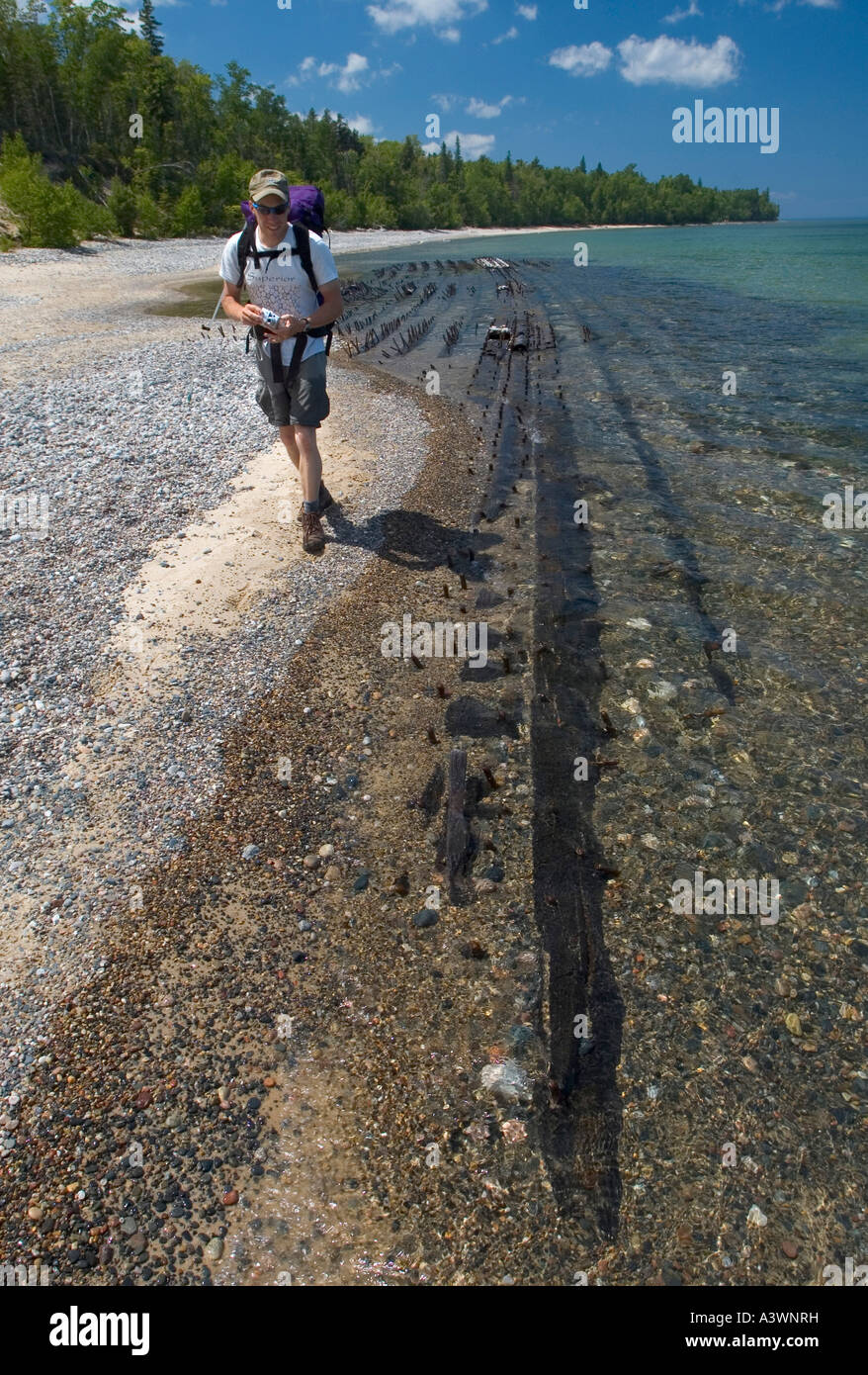 A backpacker hikes past a shipwreck on a beach near Au Sable Point in ...